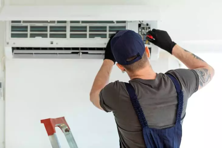 technician inspecting/ fixing a central air conditioning unit