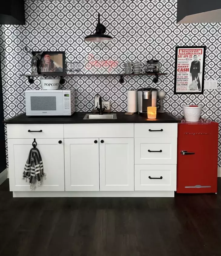 Bar basah dengan lemari putih, kulkas merah, dan backsplash hitam putih bermotif.