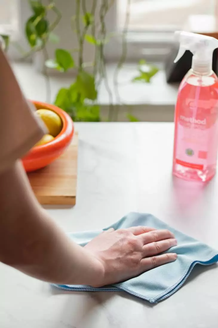 Küchenfläche mit Mikrofasertuch reinigen, Allzweckreiniger-Sprühflasche im Rahmen