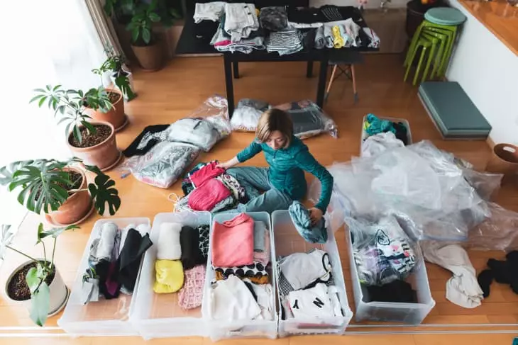 una mujer organiza la ropa en el salón de su casa.