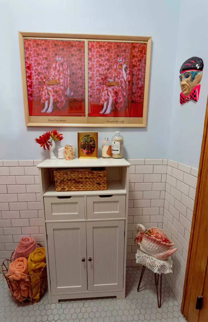 Ingelijst rood kunstwerk boven kast in badkamer