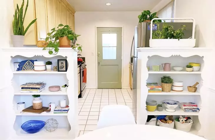 Plantas y platos en estantes que dividen la cocina y el comedor