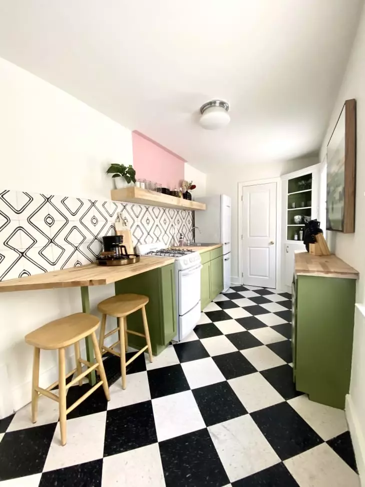 Cocina con piso de tablero de ajedrez en blanco y negro, gabinetes inferiores verdes y placa para salpicaduras con diseño de diamantes