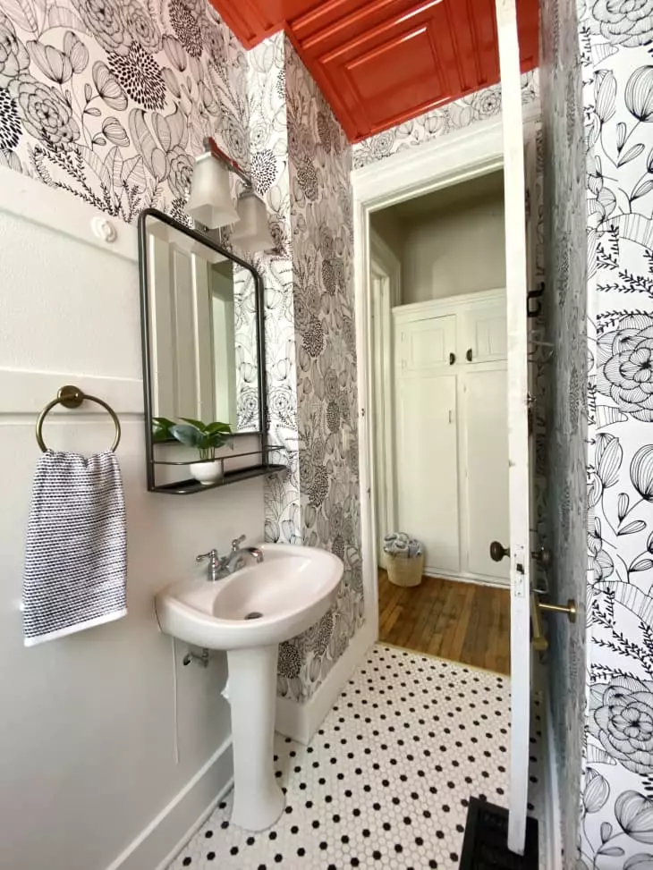 Cuarto de baño con papel tapiz floral y techo naranja