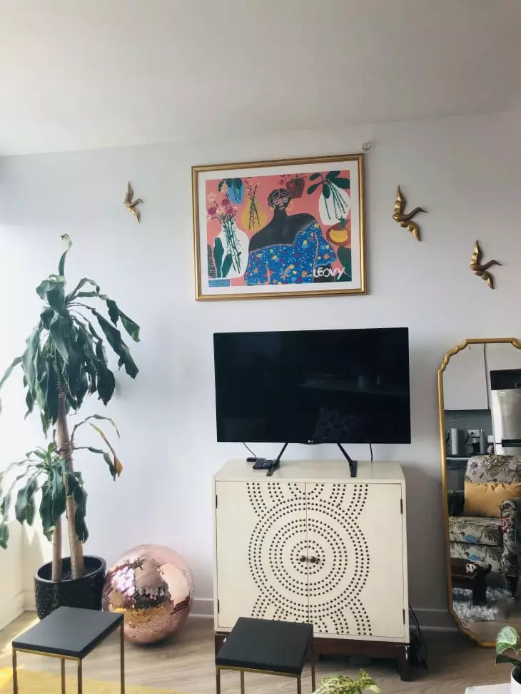 TV di atas kabinet dan karya seni berwarna-warni di dinding di atas