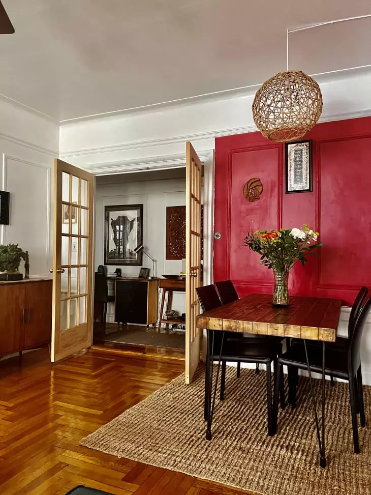Mesa de comedor en habitación con pared de acento rojo