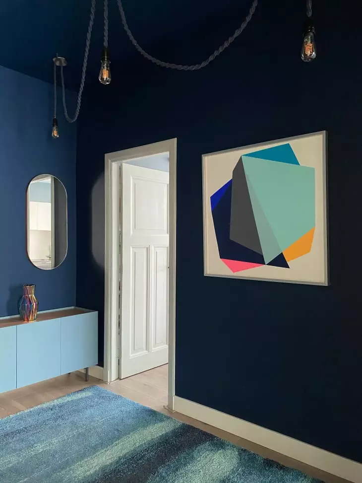 Habitación con paredes azul marino y obras de arte abstractas en la pared