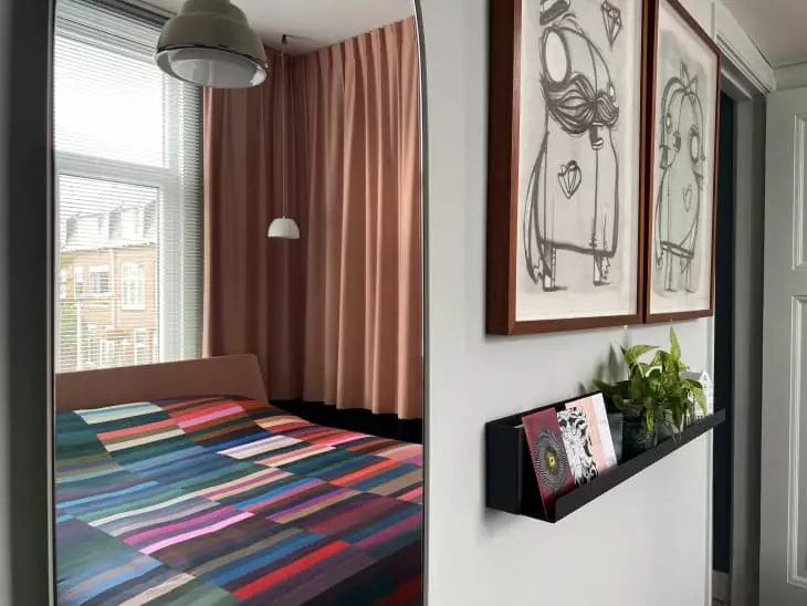 Refleksi kamar tidur dengan seprai modern berwarna-warni di cermin