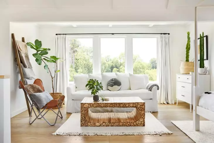 Fire stolper seng og kommode i et vakkert hvitt, rustikk moderne design gårdshus, lite hus soverom med en hvit lin sofa og kaktus på kommode.