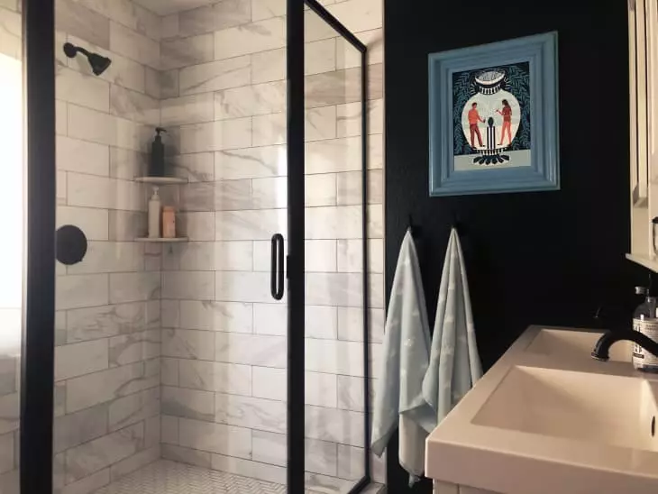 Vonios kambaryje stovintis dušas su marmurinėmis plytelėmis ir stiklu