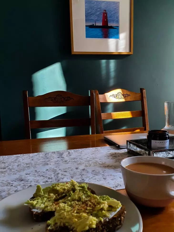 Valgomojo stalas kambaryje su tamsiai žaliomis sienomis