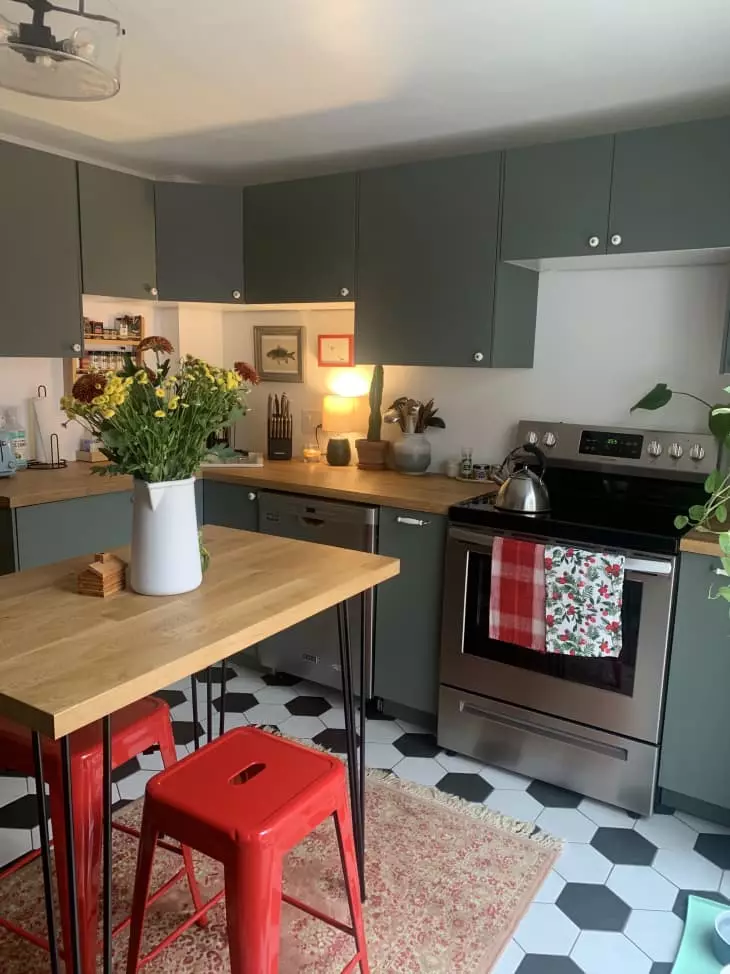 緑のキャビネットと赤いバースツールを備えたキッチン