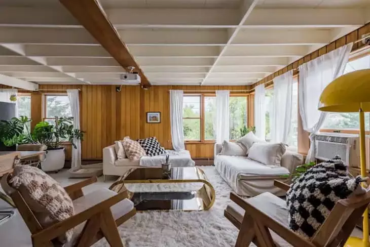 Obývacia izba s dreveným obkladom a bielymi priesvitnými závesmi