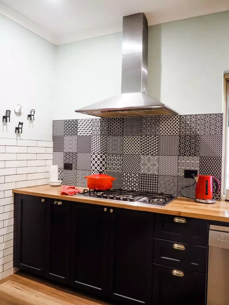 Estufa y campana en la esquina de la cocina con placa para salpicaduras de azulejos estampados en blanco y negro