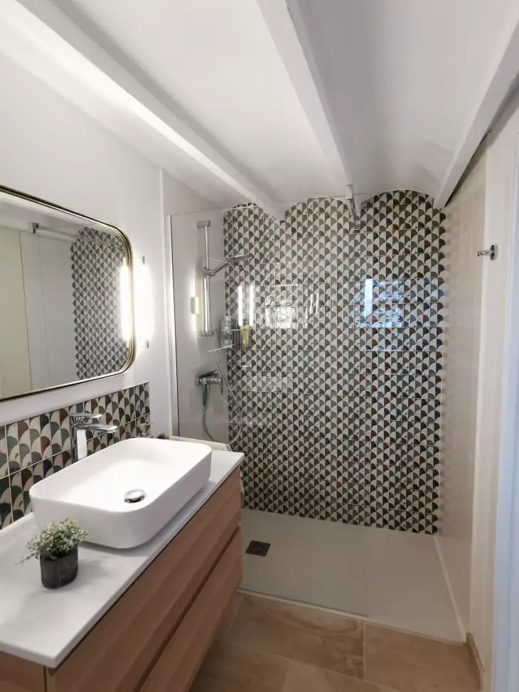 Badkamer met staande douche met glazen voorkant en geschulpte tegel