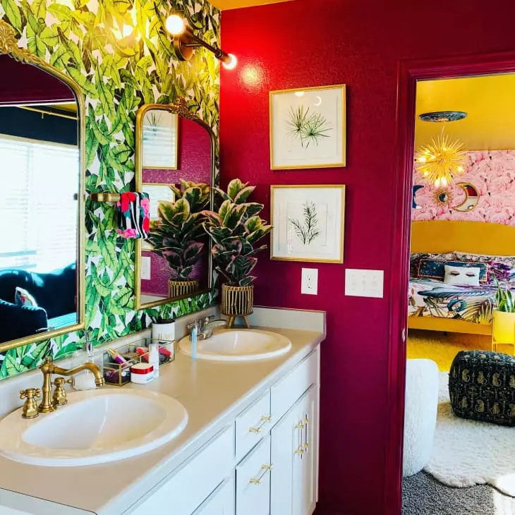 Banheiro com papel de parede verde em folha de palmeira atrás de espelhos