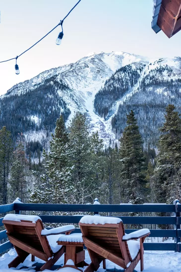 Alpendre com duas cadeiras Adirondack de frente para montanhas nevadas