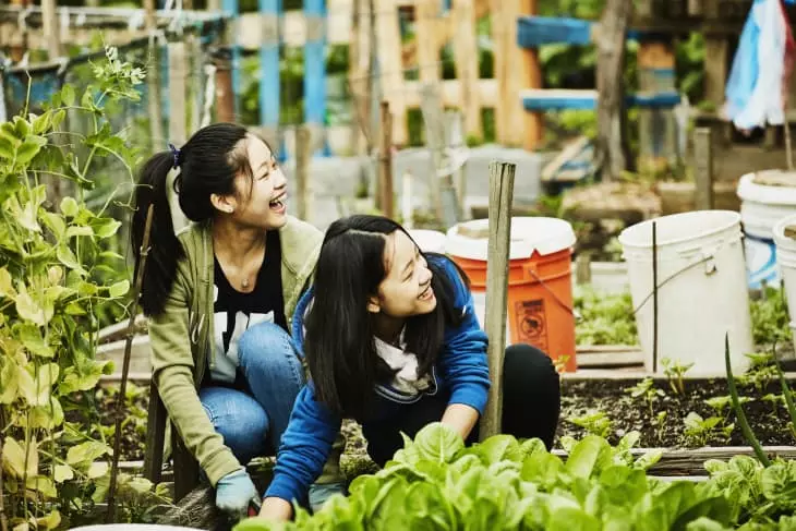 Wanita muda yang tertawa menjadi sukarelawan di taman komunitas