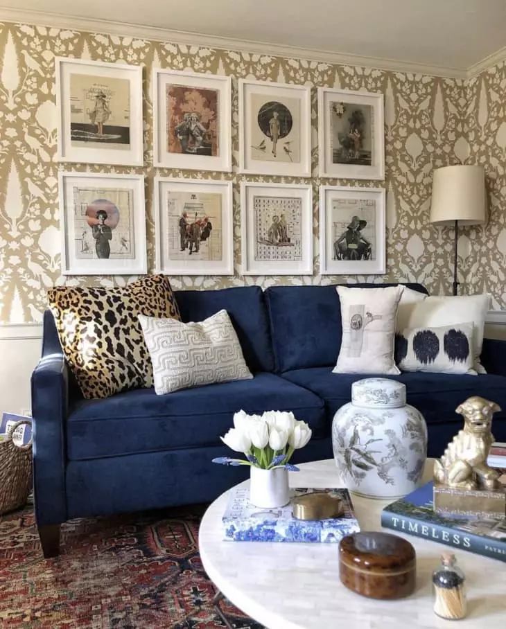 Sala na may navy couch at gintong patterned na wallpaper