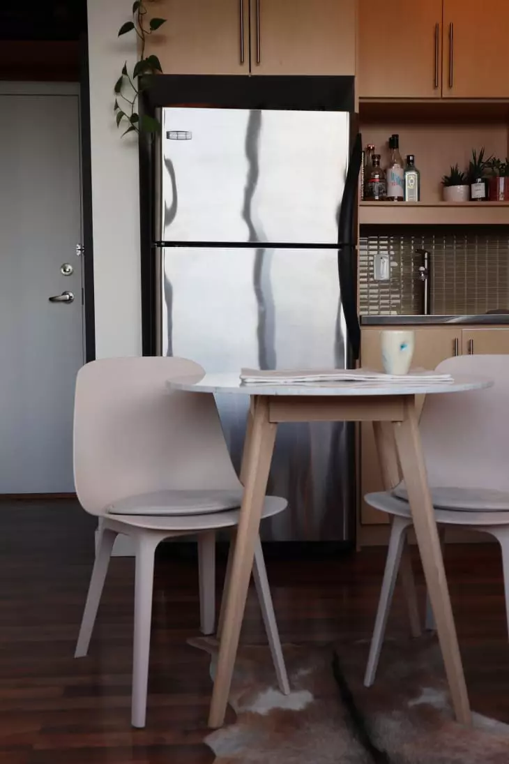 Mesa e cadeiras brancas na cozinha com geladeira de aço inoxidável