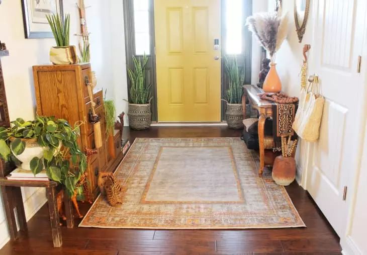 Entrada nga adunay yellow nga pultahan sa atubangan ug vintage rug