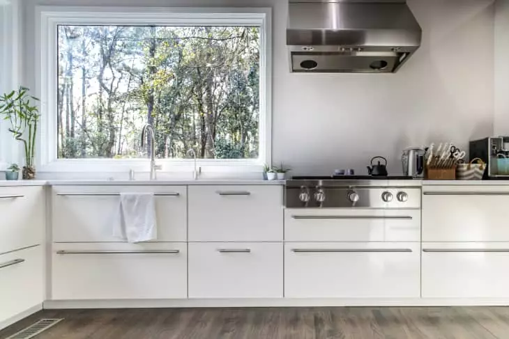 пространа велика модерна савремена недавно реновирана бела кухиња недавно ажурирана врхунским апаратима, подовима од тврдог дрвета, прозорима за слике и белим ормарићима.