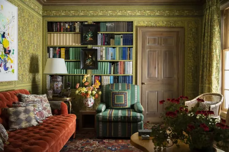 غرفة مكتبة خضراء بها أريكة برتقالية