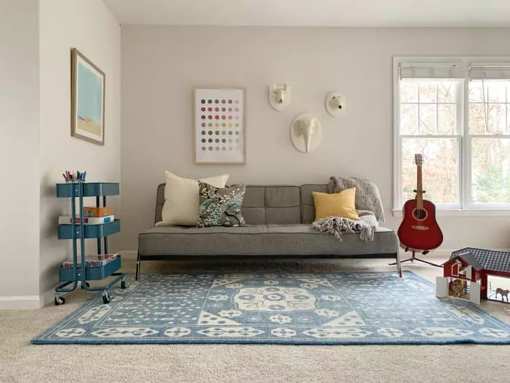 Lekrum med grå soffa, gitarr, blå matta och blå vagn