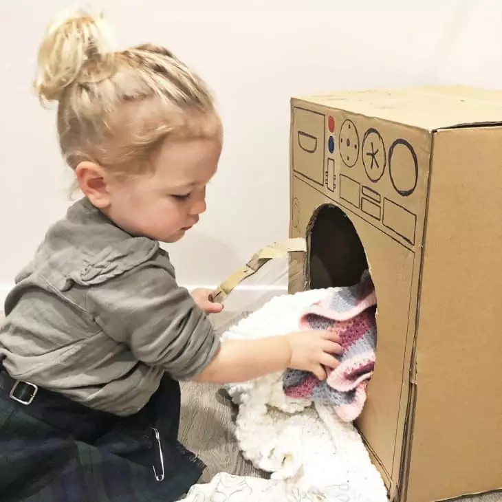 Enfant jouant avec une machine à laver en carton