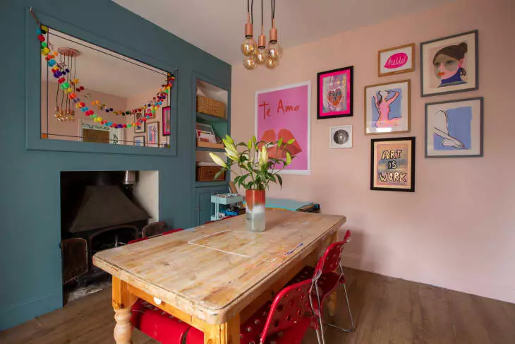 Salle à manger avec un mur bleu sarcelle avec une étagère et une cheminée intégrées et un mur rose avec des œuvres d'art encadrées