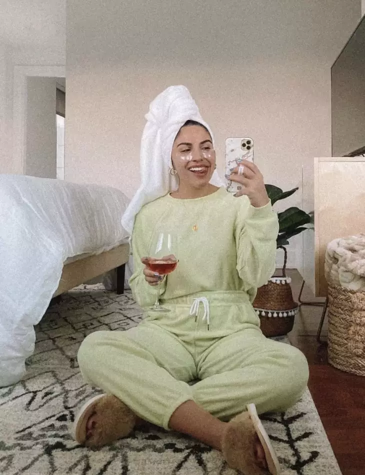 Γυναίκα με τουρμπάνι πετσέτας, μάσκα προσώπου και παντόφλες με ποτήρι κρασί