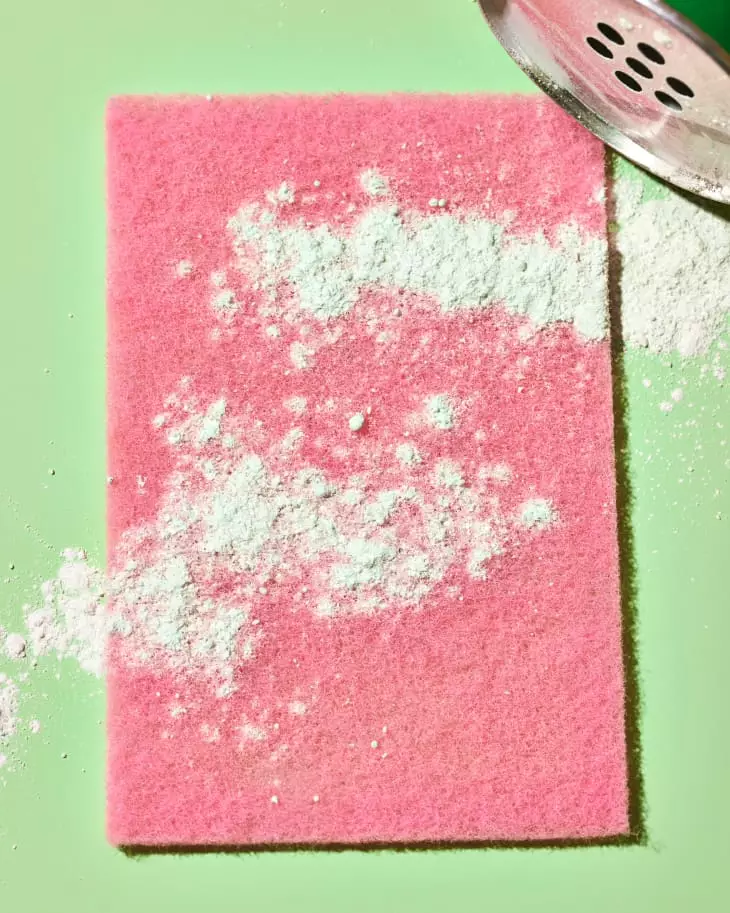 Почистващ прах върху розова подложка за почистване на зелен фон