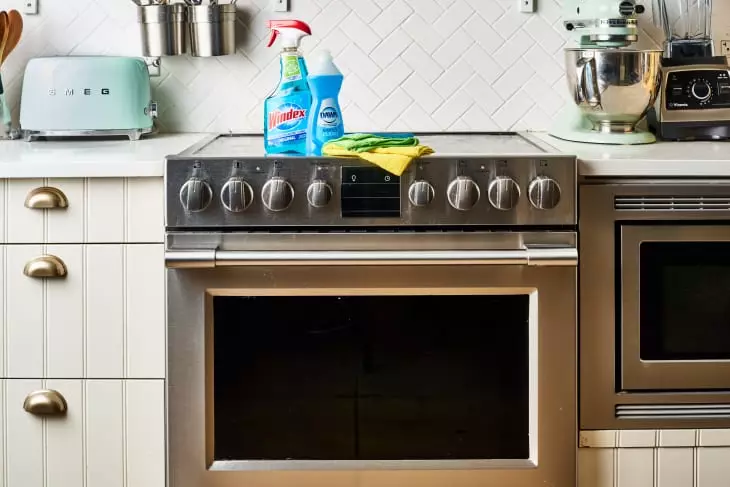 Un horno dentro de una cocina con productos de limpieza cerca