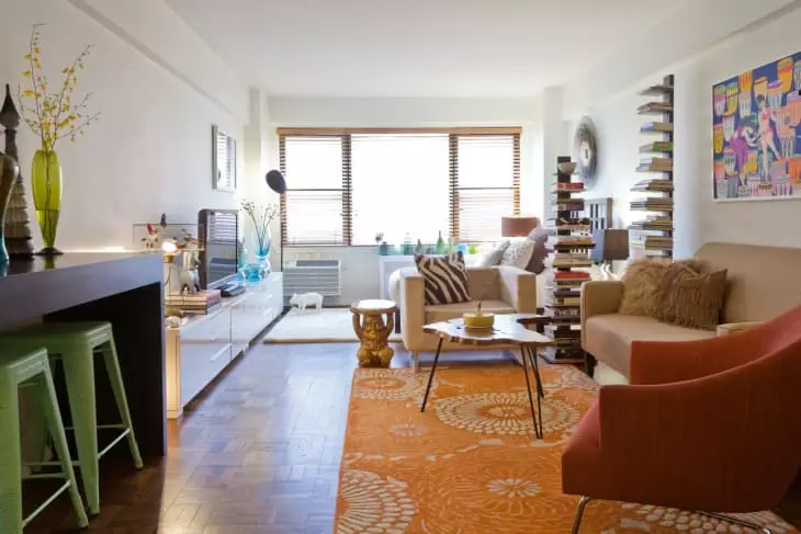Apartamento estudio moderno y colorido con alfombra naranja y paredes blancas